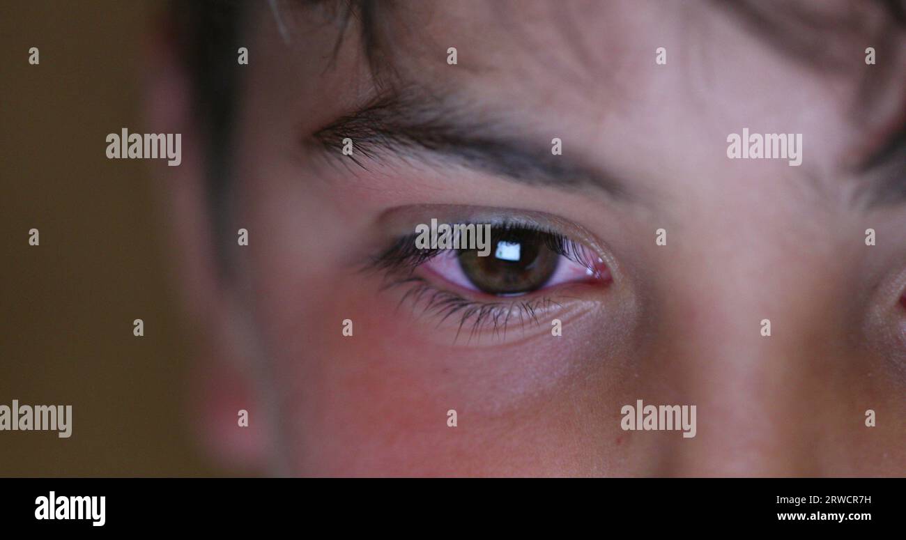 Young boy eyes staring at screen at night. Close-up of child face ...