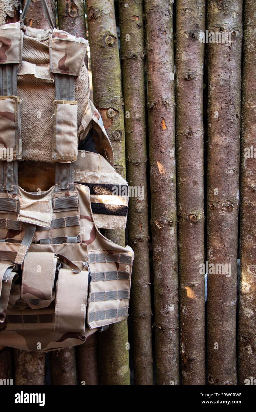 An old worn-out soldier's vest hangs on a wooden wall made of logs, a ...