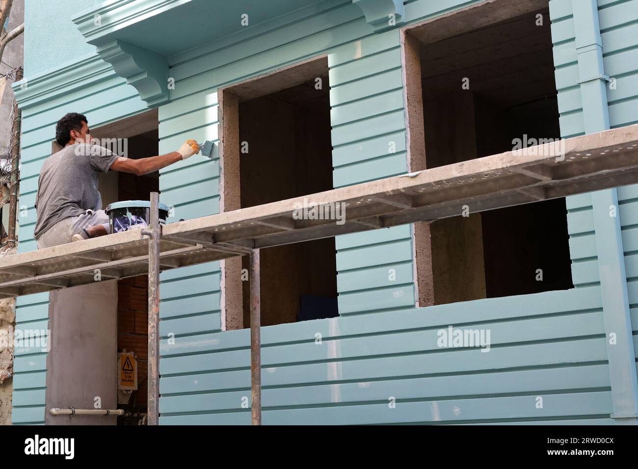 A decorator painting the outside of a house in the Balat district of ...
