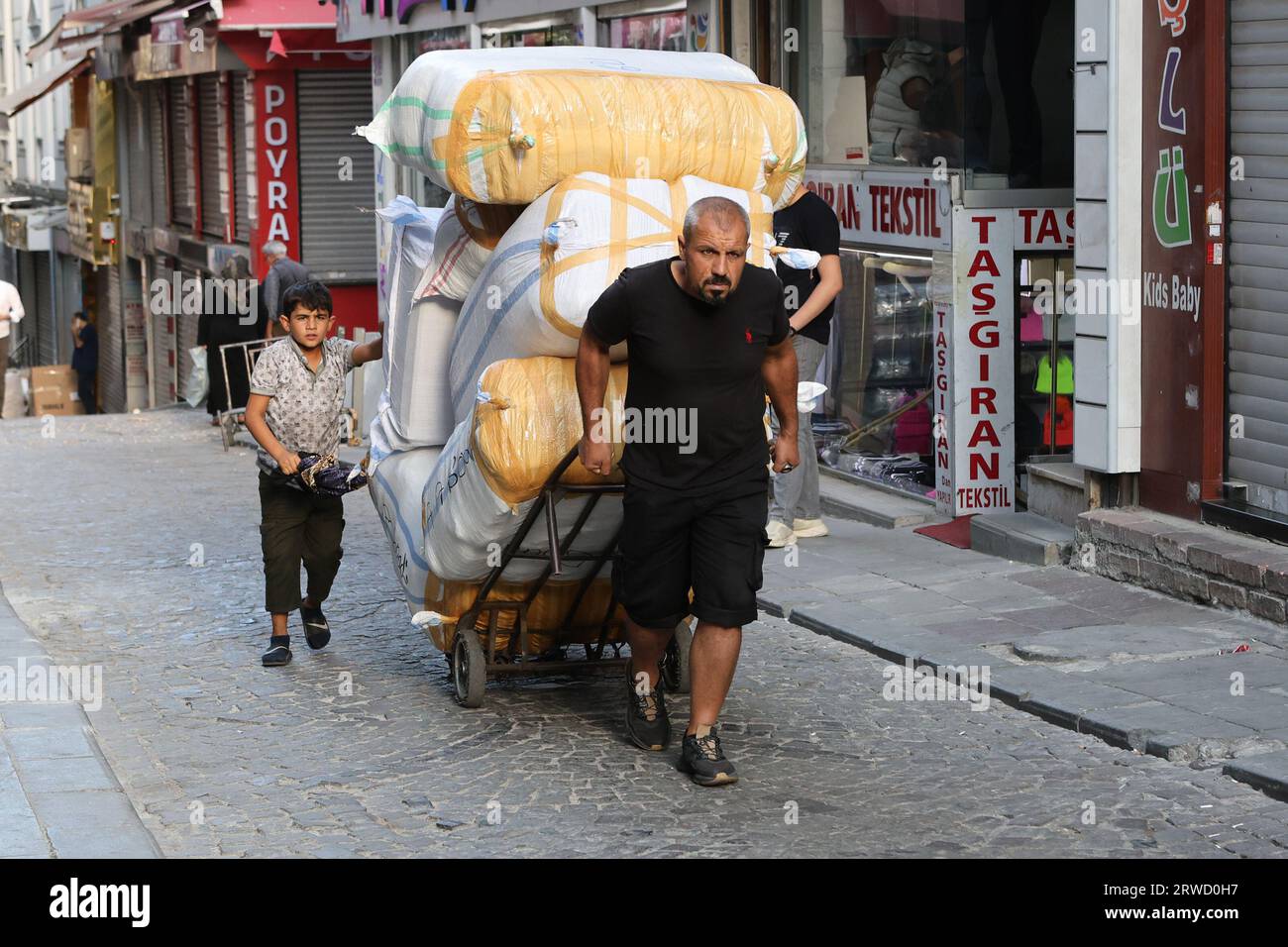 A man with his son haul a trolley laden with packages through the ...