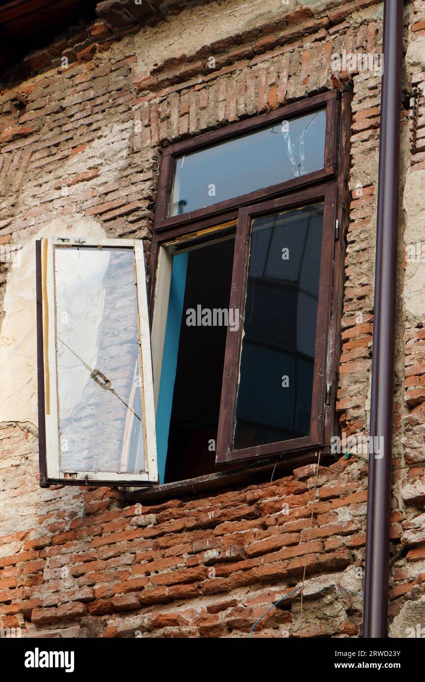 Old abandoned house facade with decaying brick wall and window hanging ...