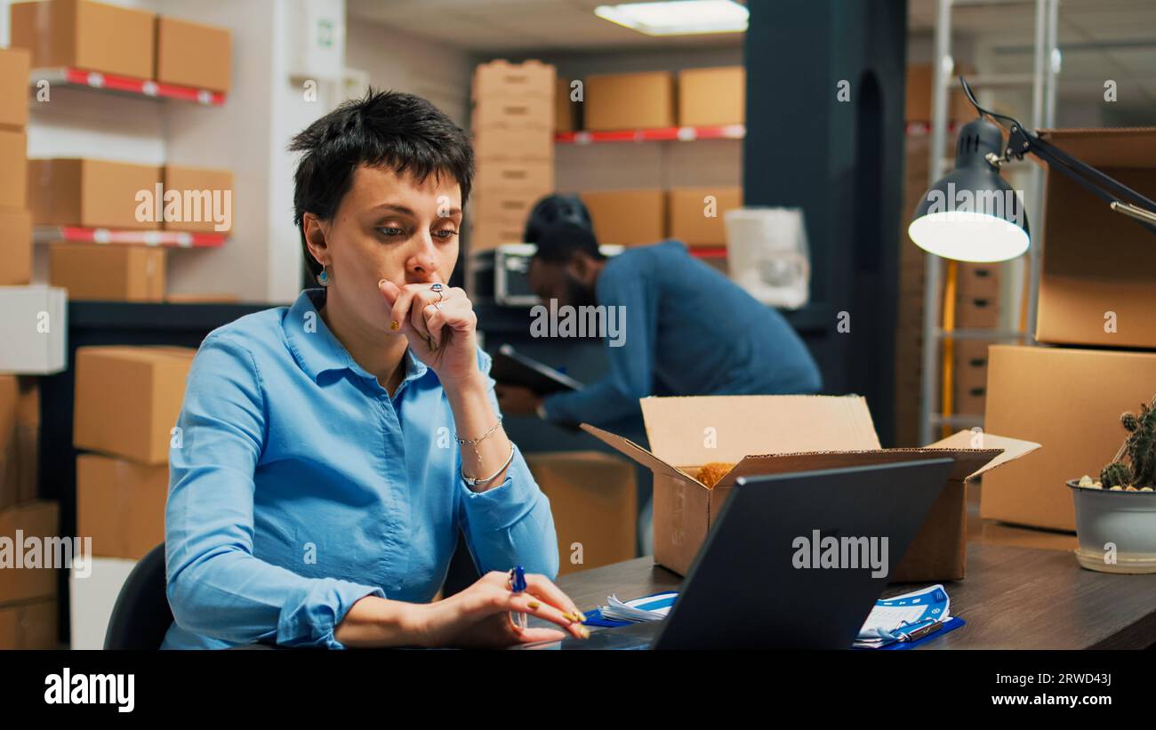 Woman employee analyzing goods from warehouse shelves, looking at ...