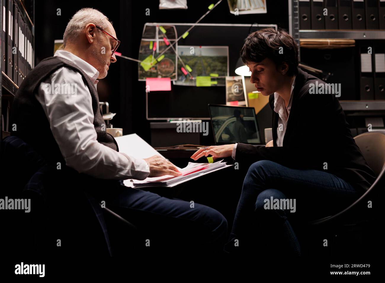 Old investigator showing confidential files to woman agent, discussing ...