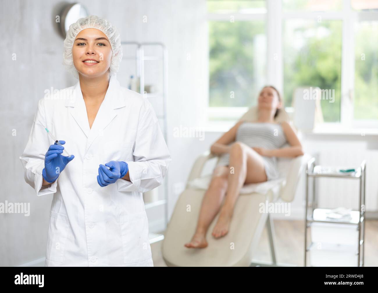 Nurse in disposable cap with syringe in hand and conducts preparatory ...