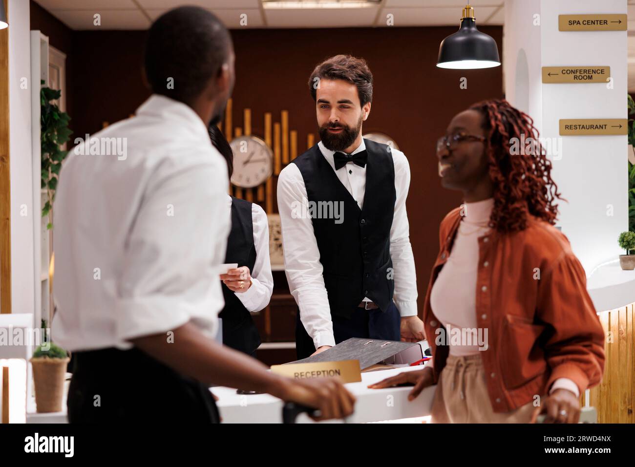 Hotel staff welcoming guests at counter, providing excellent check in ...
