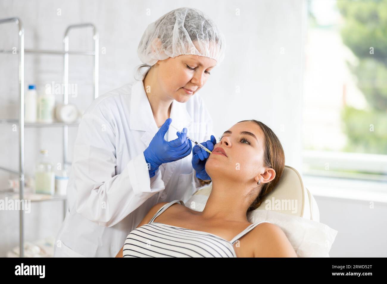 Doctor gives injection and performs procedure of lip augmentation of ...