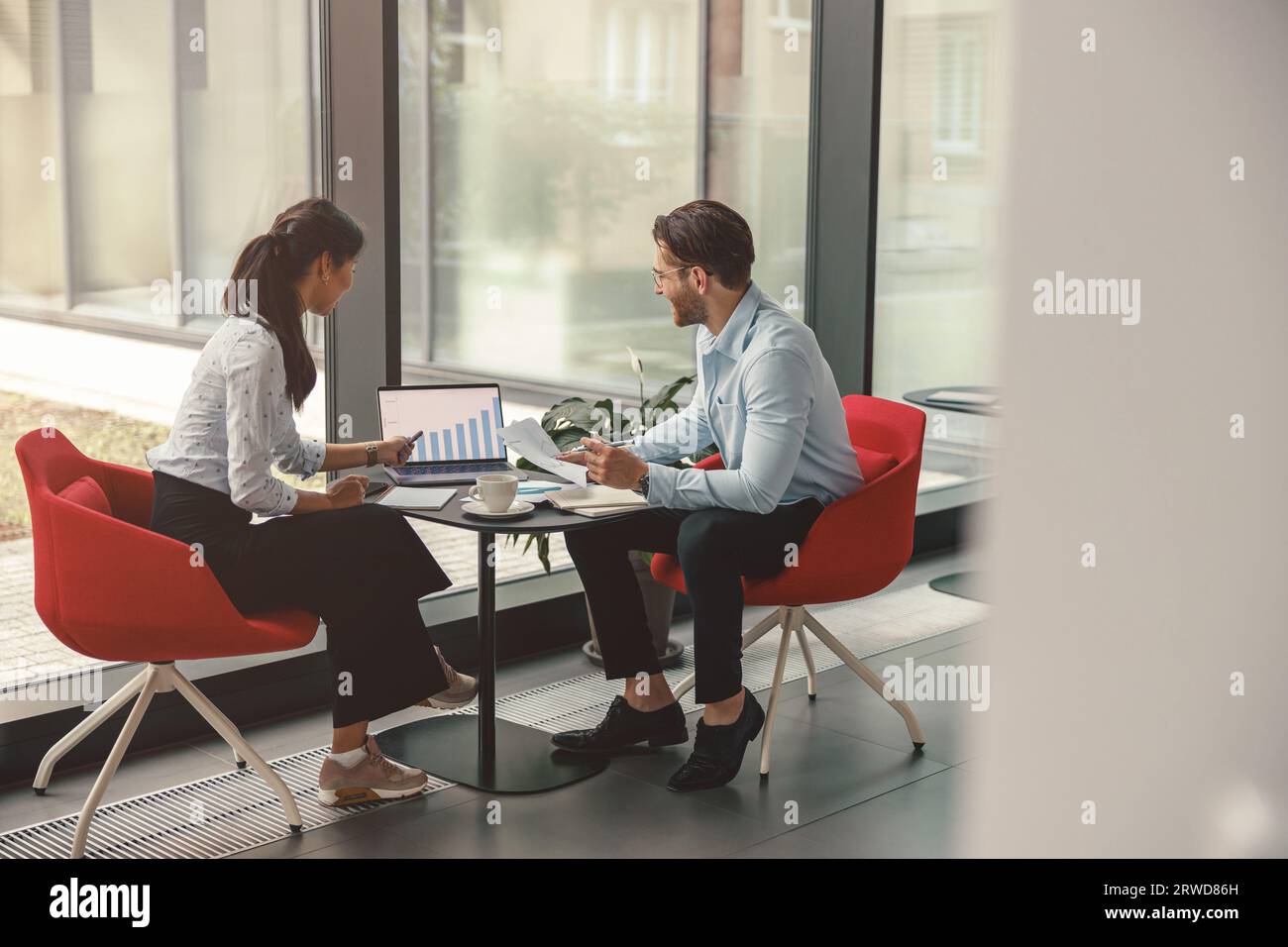 Two diverse business colleagues working together on project sitting in ...