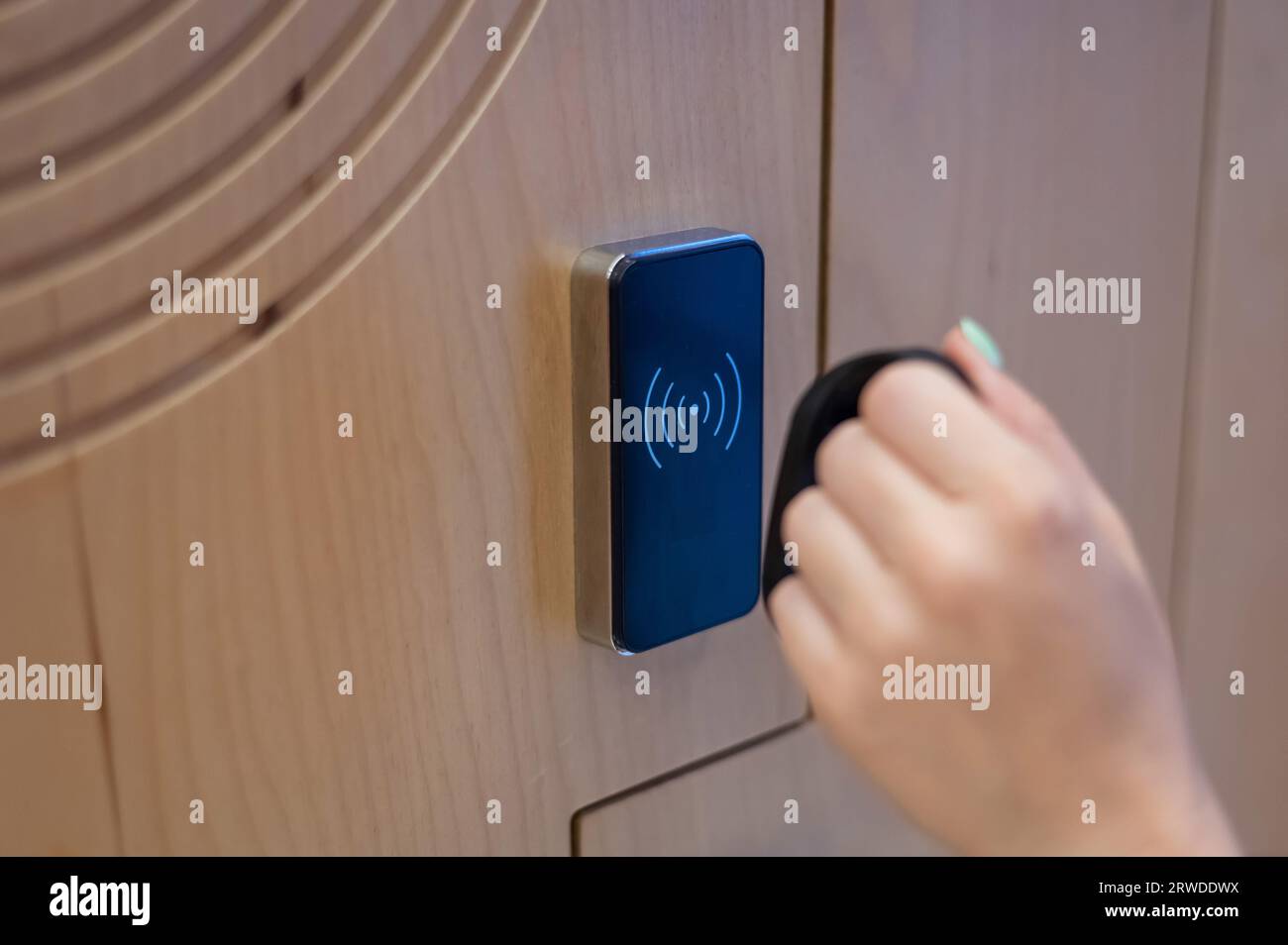 A woman opens the electronic lock of a cubicle in a locker room with a ...
