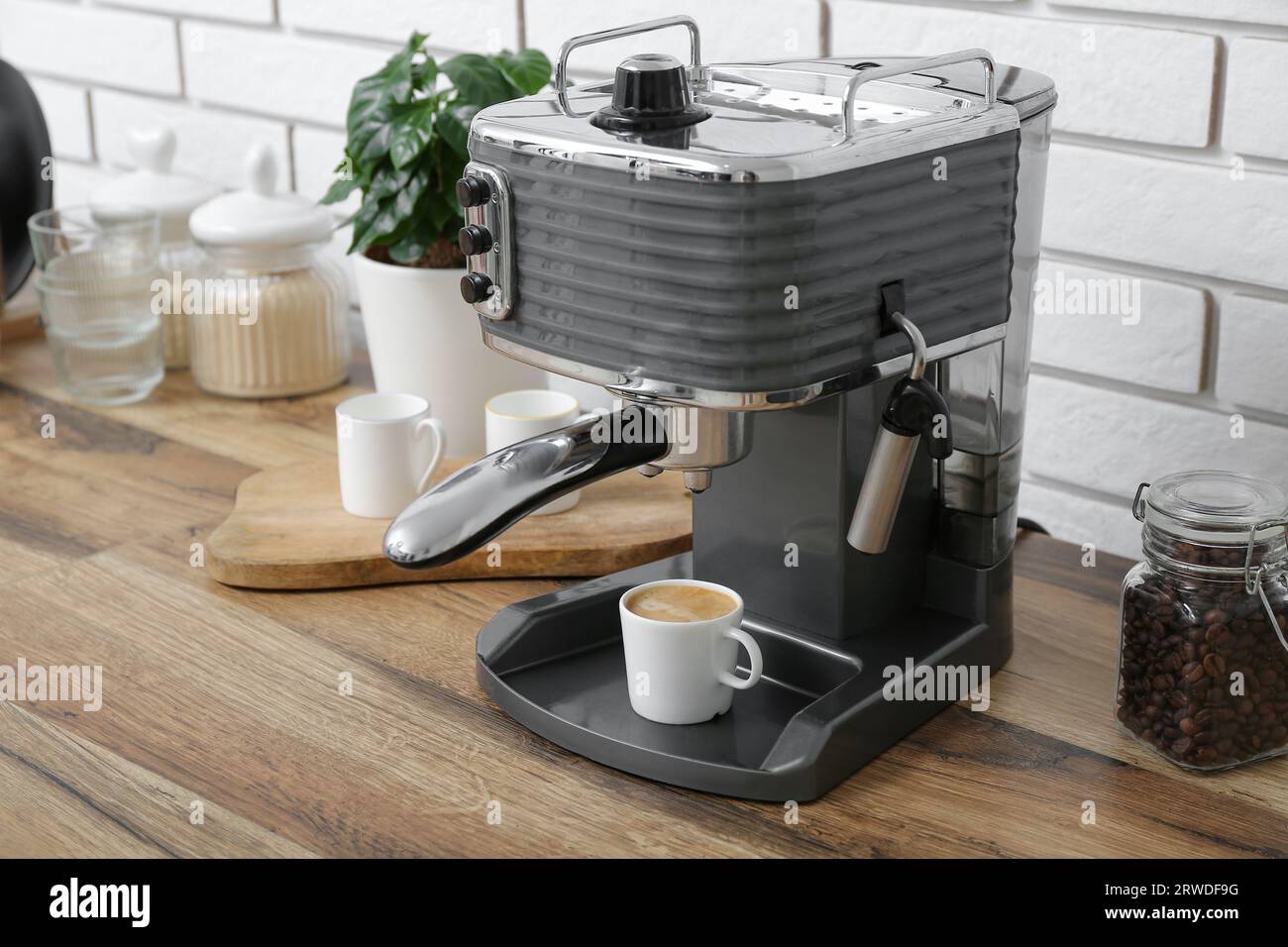 Modern coffee machine with cup of hot espresso on table in kitchen ...
