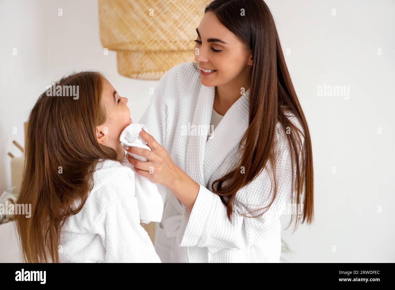 Happy mother wiping her little daughter's face in bathroom Stock Photo ...