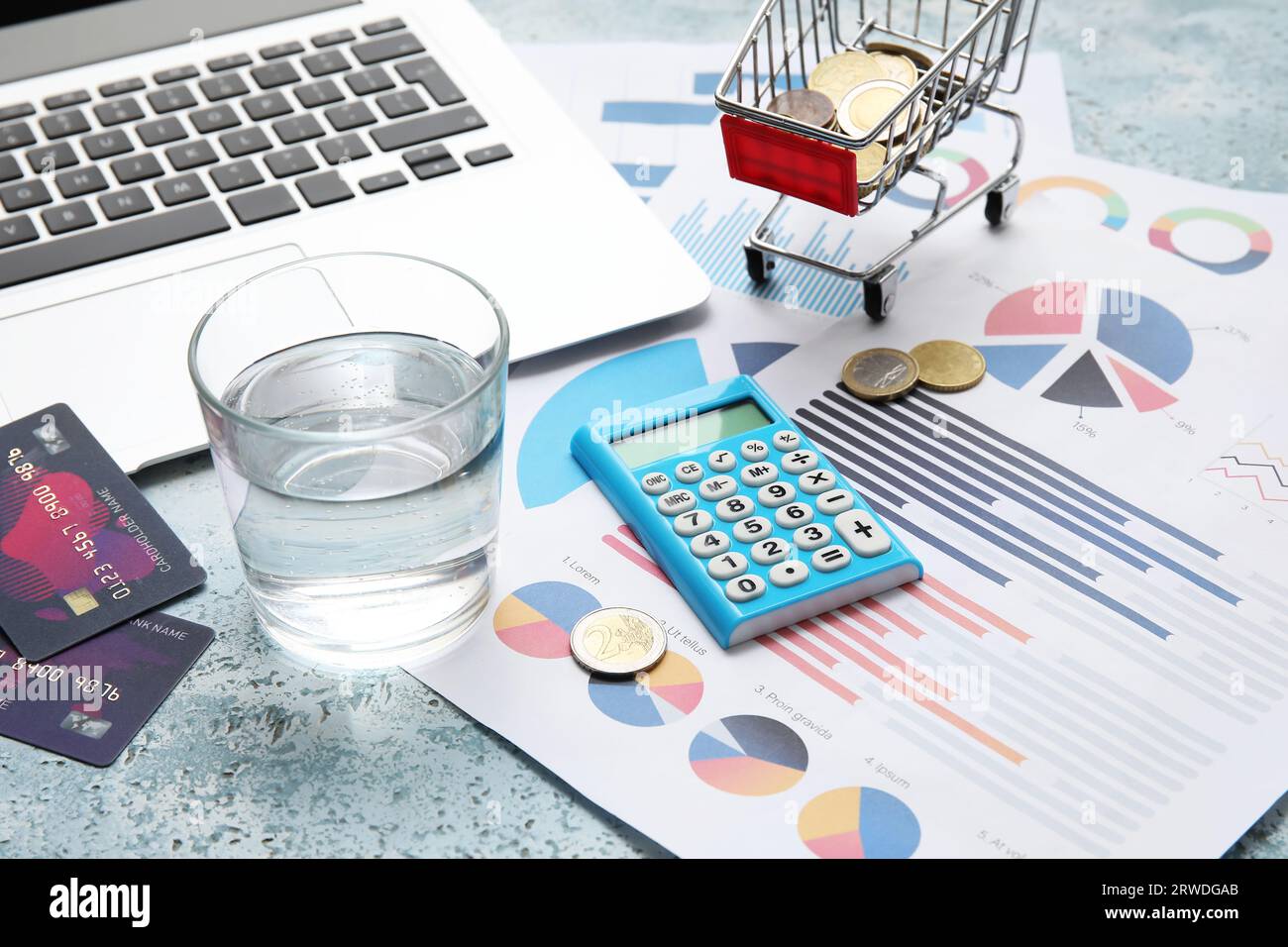 Glass of water, credit cards, calculator and charts on blue grunge ...