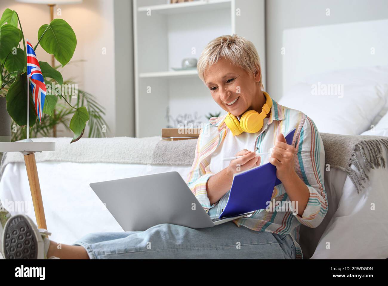 Mature woman learning English language online in bedroom Stock Photo ...