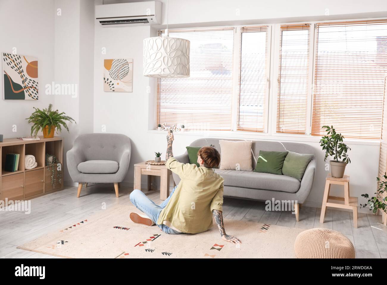Young man turning on air conditioner at home, back view Stock Photo - Alamy