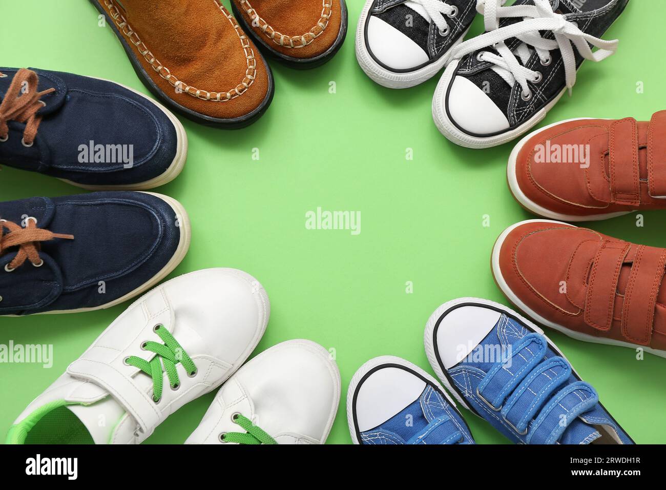 Frame made of different child's shoes on green background, closeup ...