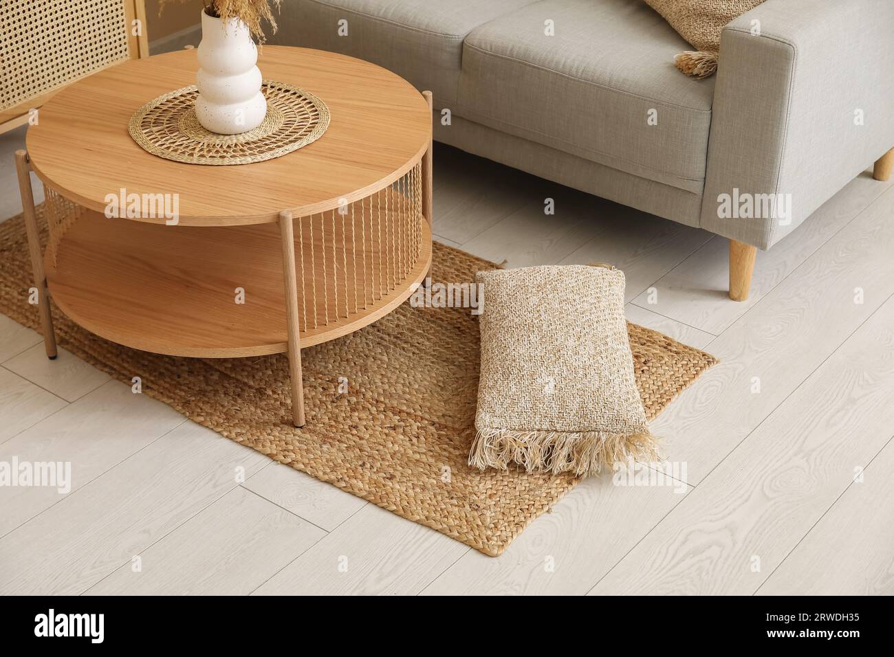 Interior of living room with wicker rug, wooden coffee table and grey ...