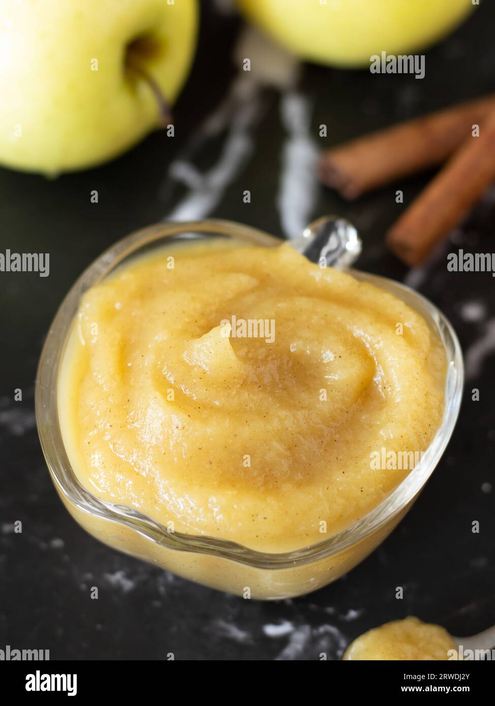 Homemade apple puree in a glass bowl with a swirl on top, cinnamon, and ...