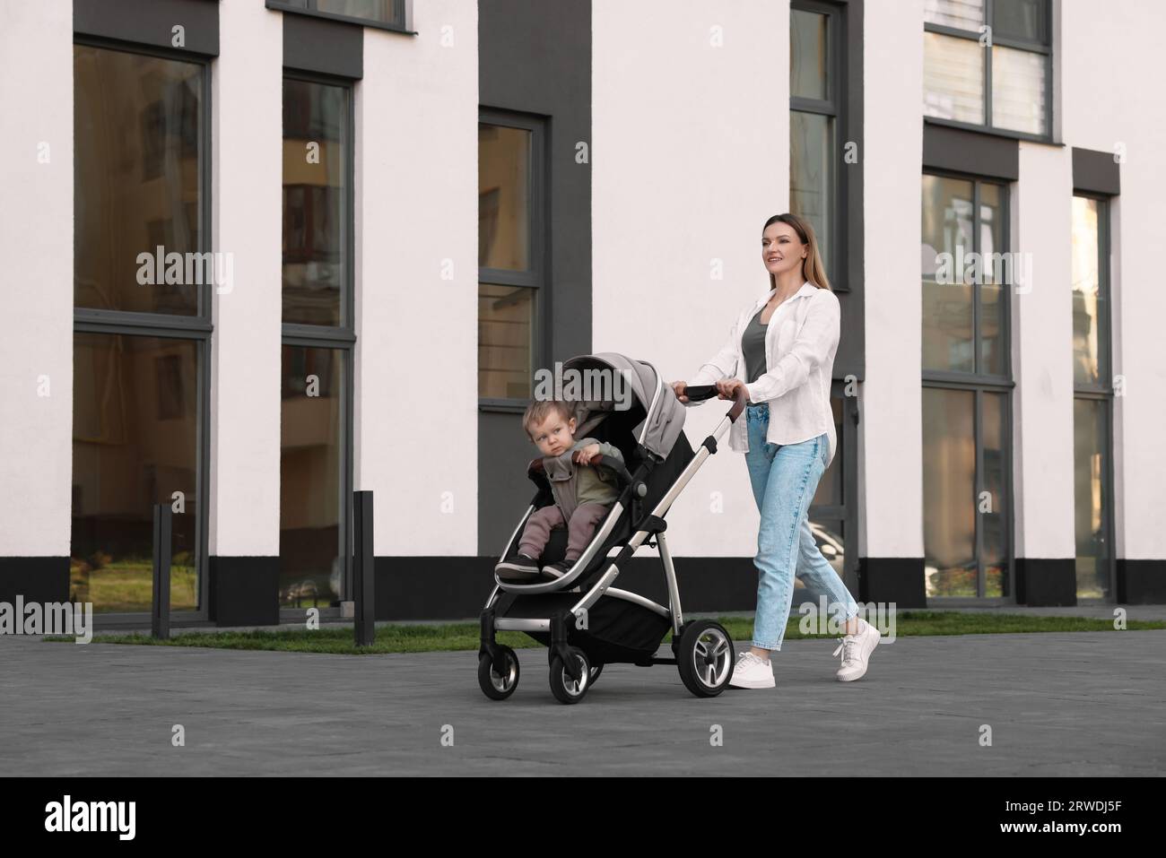 Happy nanny with cute little boy in stroller walking outdoors Stock ...