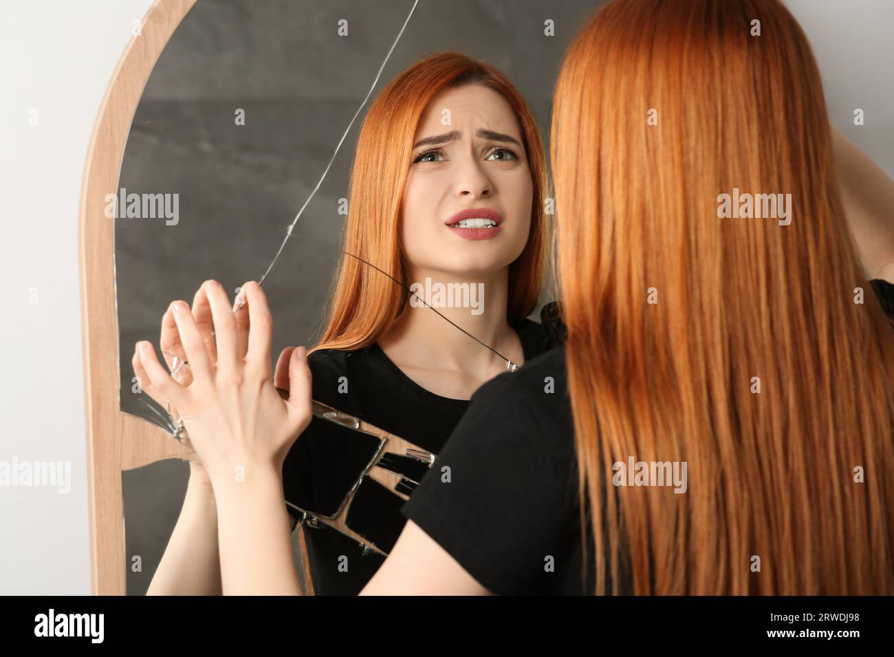 Mental problems. Disappointed young woman looking at herself in broken ...