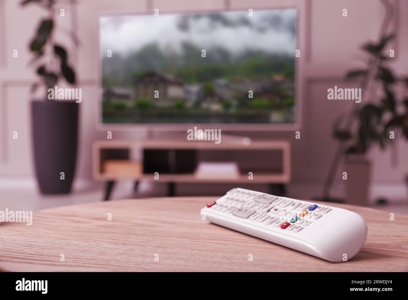Remote control on wooden table and TV screen in room, selective focus ...