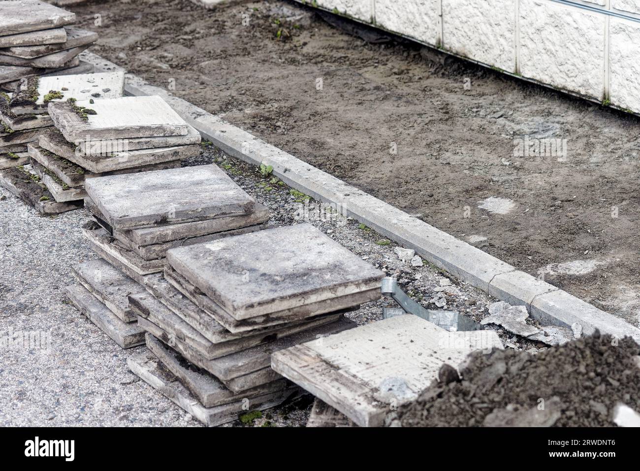 Facing concrete tiles lie on ground in stack. Replacing building ...