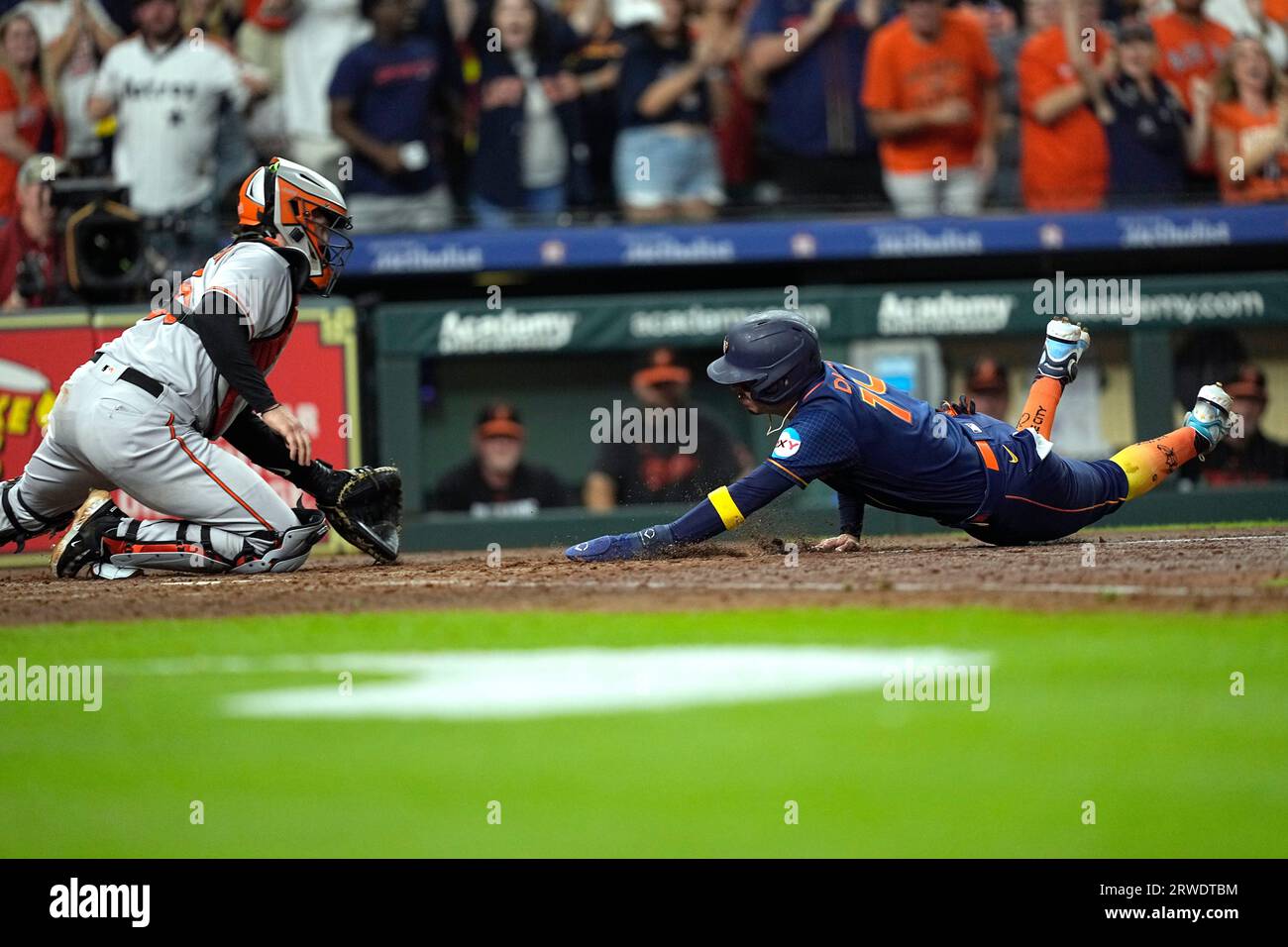 Houston Astros' Mauricio Dubon, right, dives toward home plate to score ...