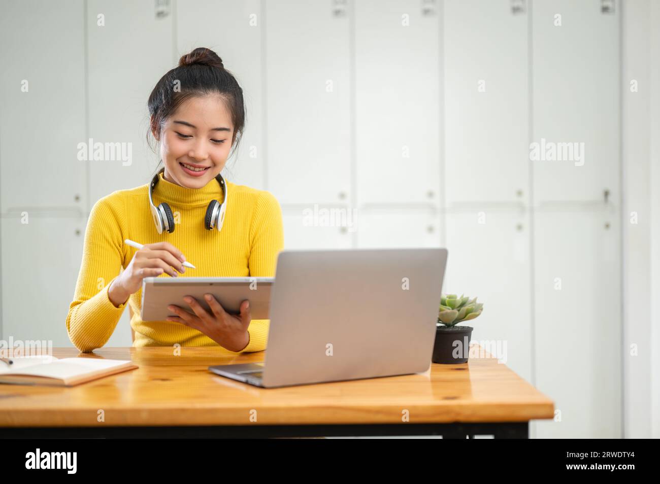 A charming young Asian female university student using her digital ...