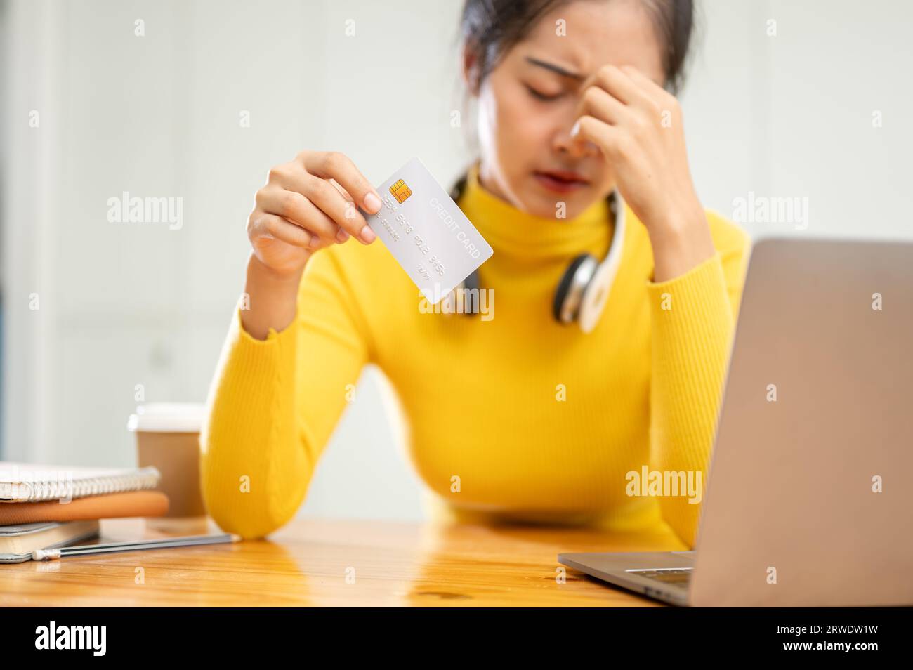 Close-up image of a stressed Asian woman holding a credit card, having ...