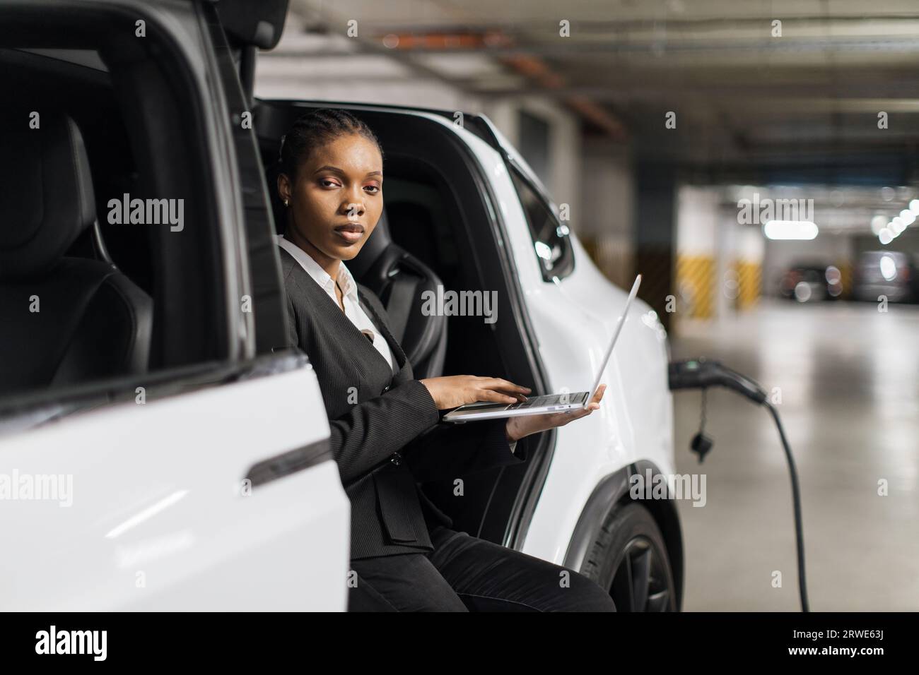 Professional operating computer in EV on charge in garage Stock Photo ...