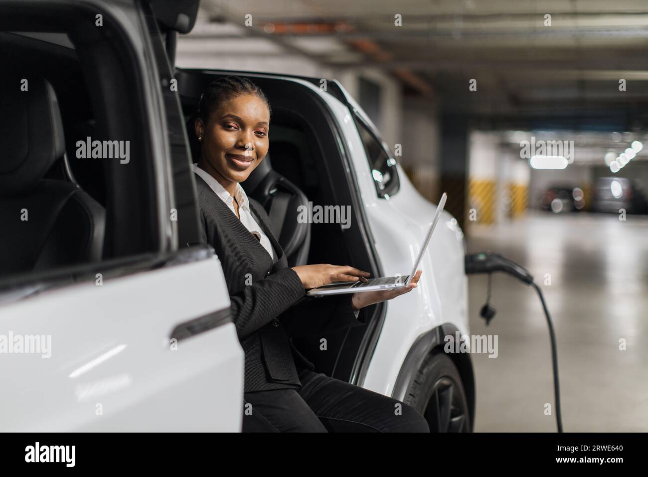 Professional operating computer in EV on charge in garage Stock Photo ...