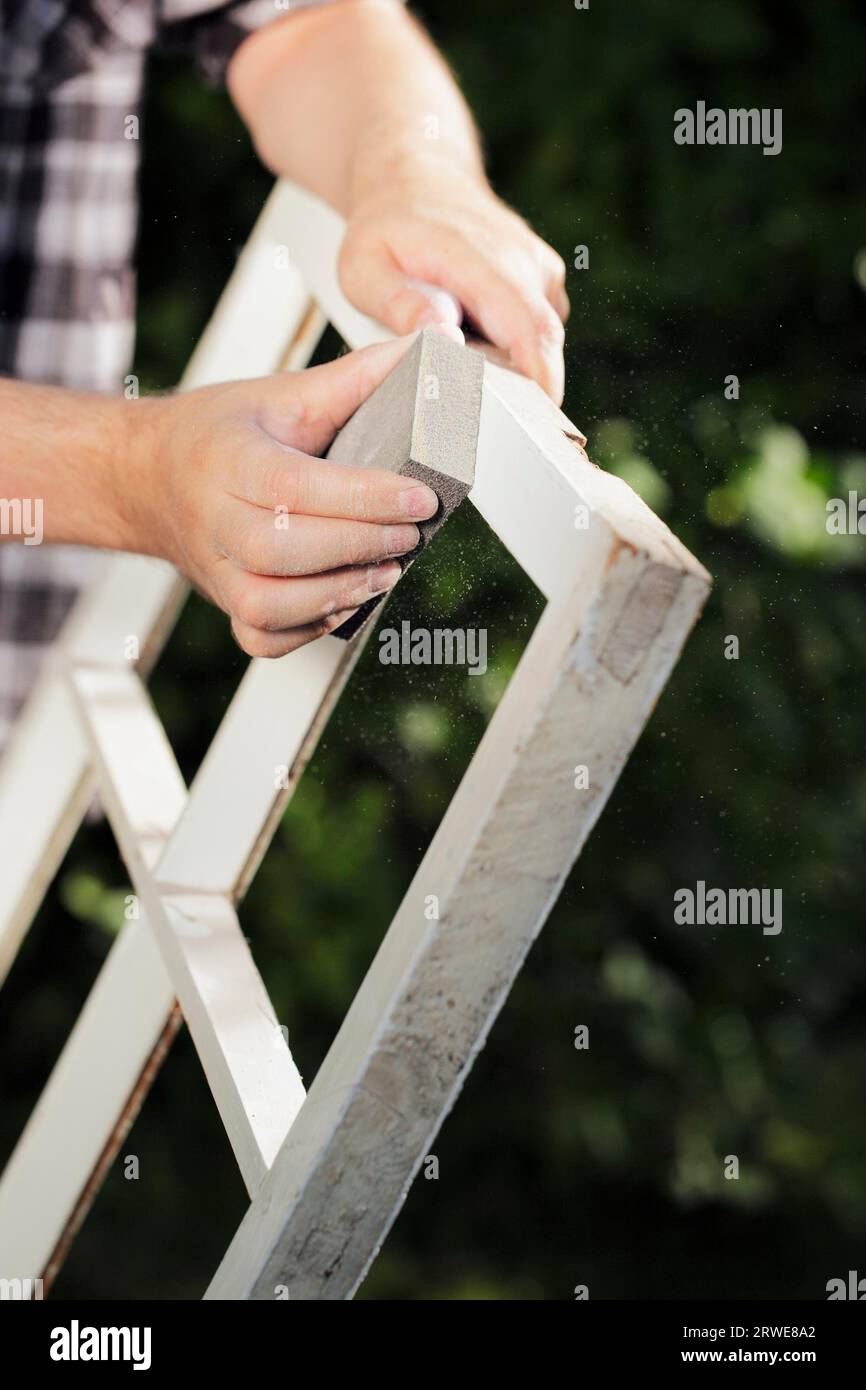 Man using Abrasive foam Block on an old window frame outdoors Stock ...