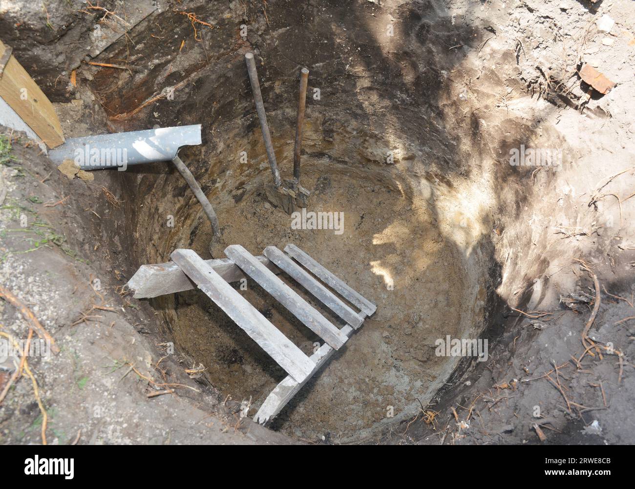 Digging a deep round hole with sewer line, drain pipe outlet for a ...