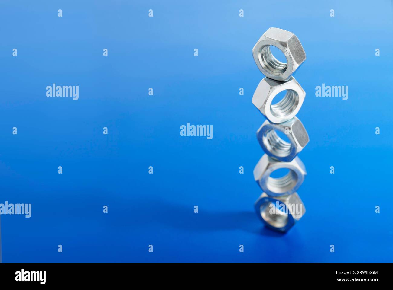 Steel nuts stacked on blue background Stock Photo - Alamy