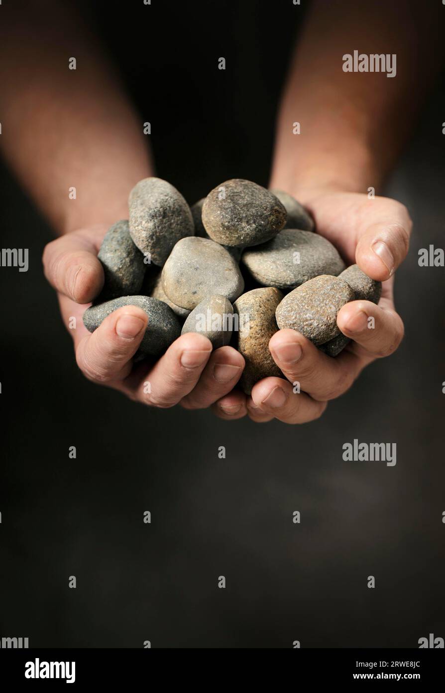 Man holding small rock pebbles in his cupped hands Stock Photo - Alamy