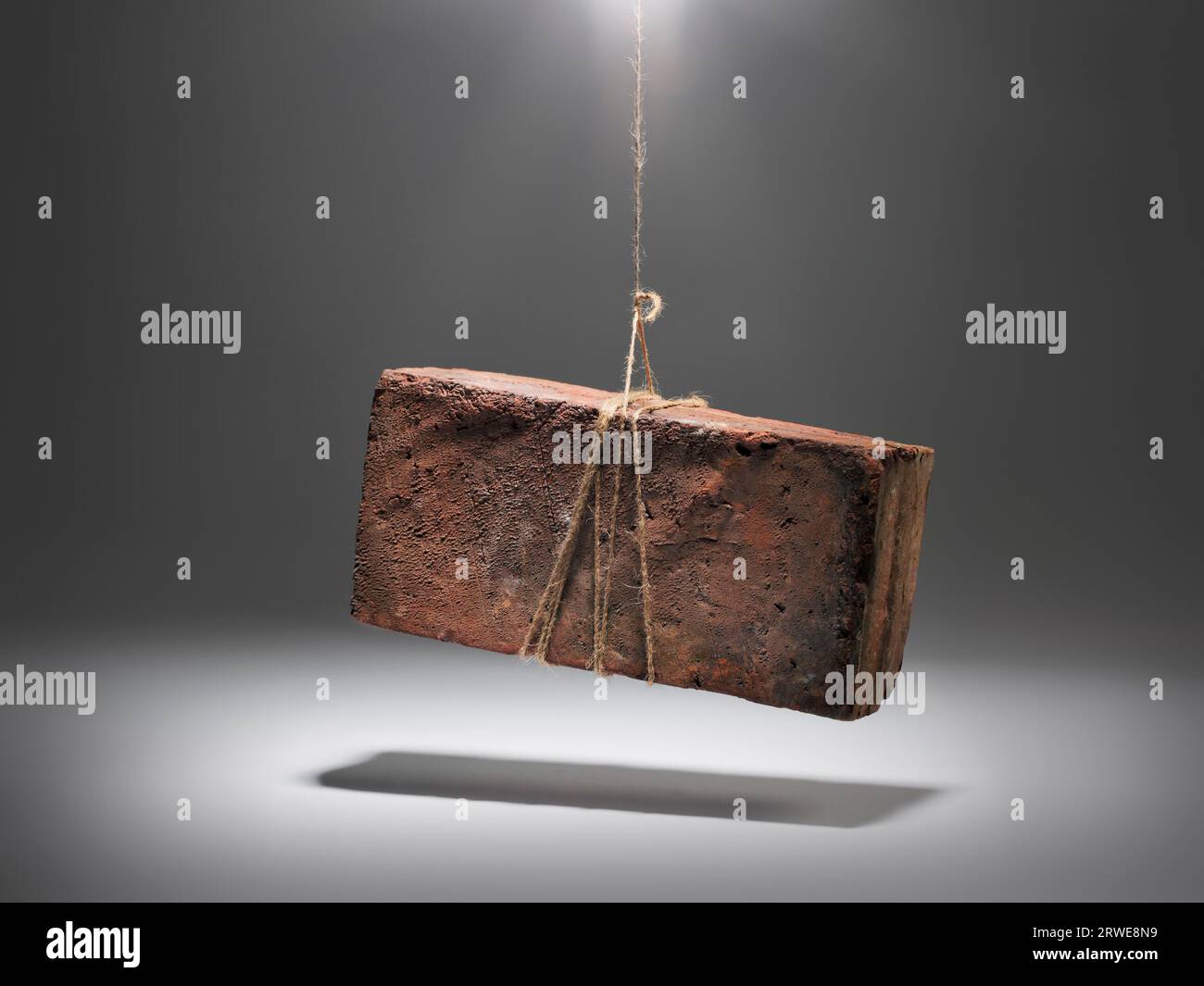 An old worn brick dangling from a string Stock Photo - Alamy