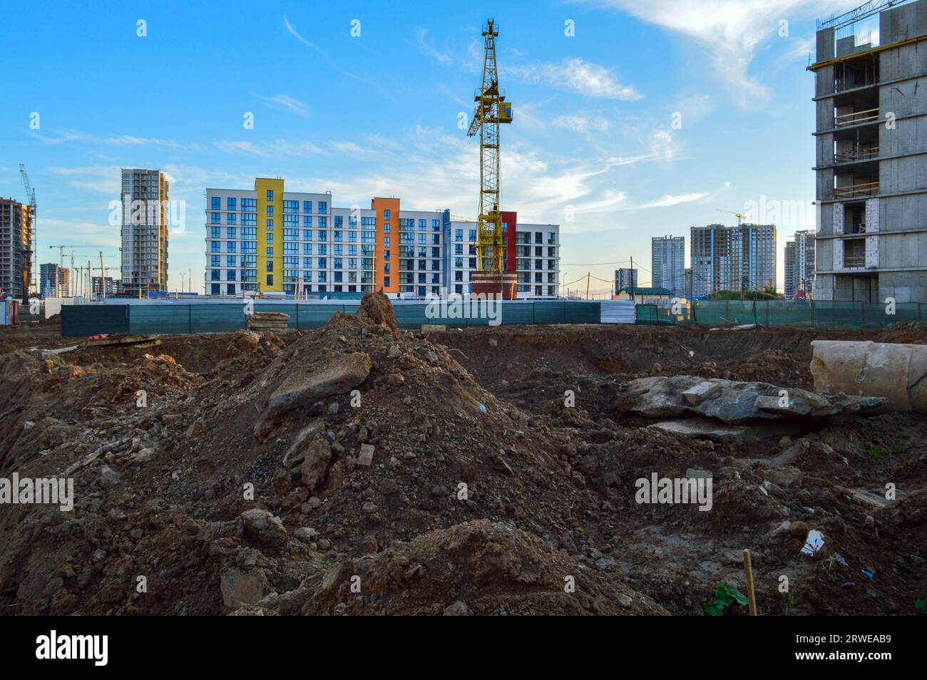 construction of a new quarter. a large crane is digging a sand ditch ...