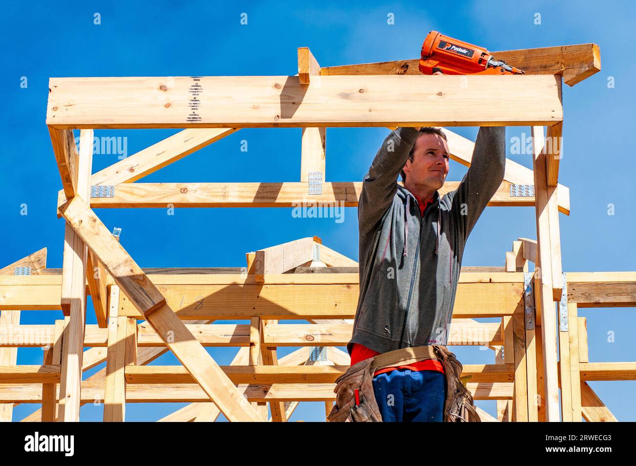 Tradesman using a nail gun in building a timber framed house in South ...