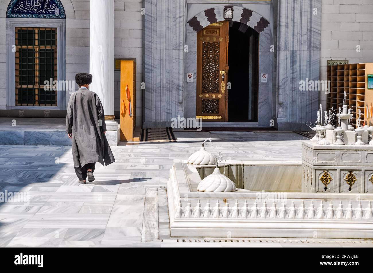 Photo of native man in long coat walking away to building made of stone ...