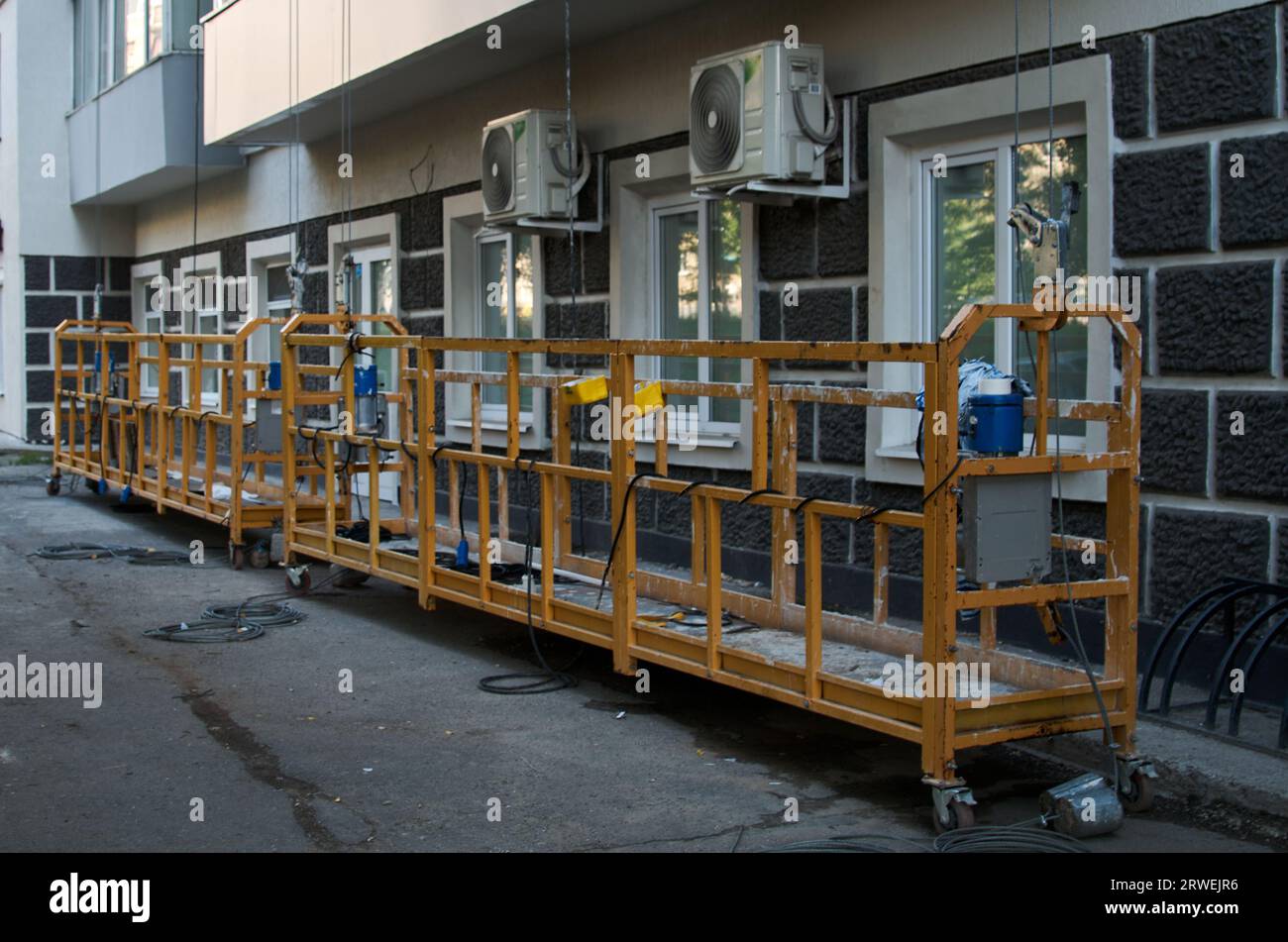 Two yellow construction overhead mobile elevators stand on the ground ...