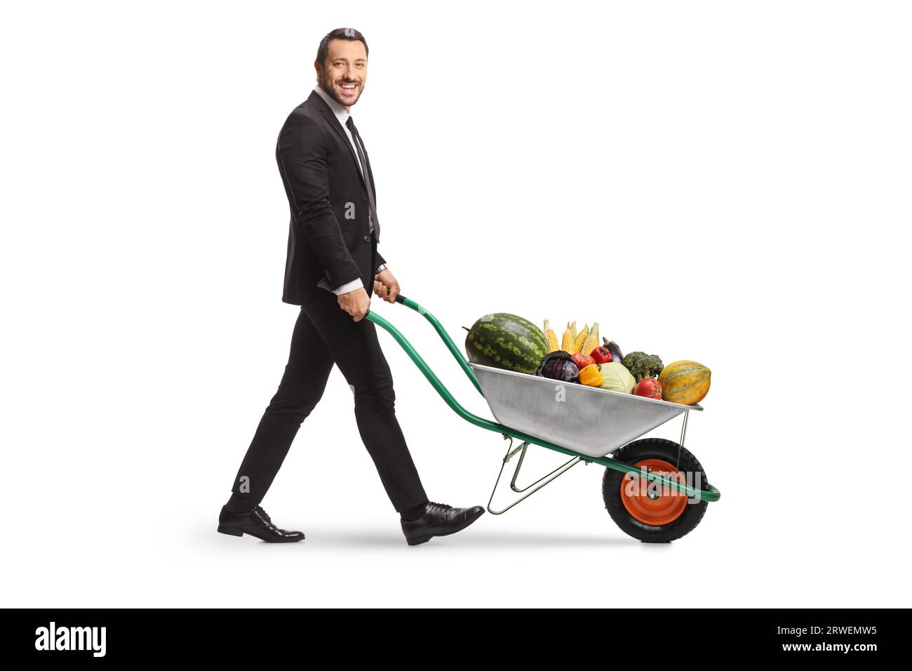 Full length profile shot of a businessman pushing a wheelbarrow full of ...