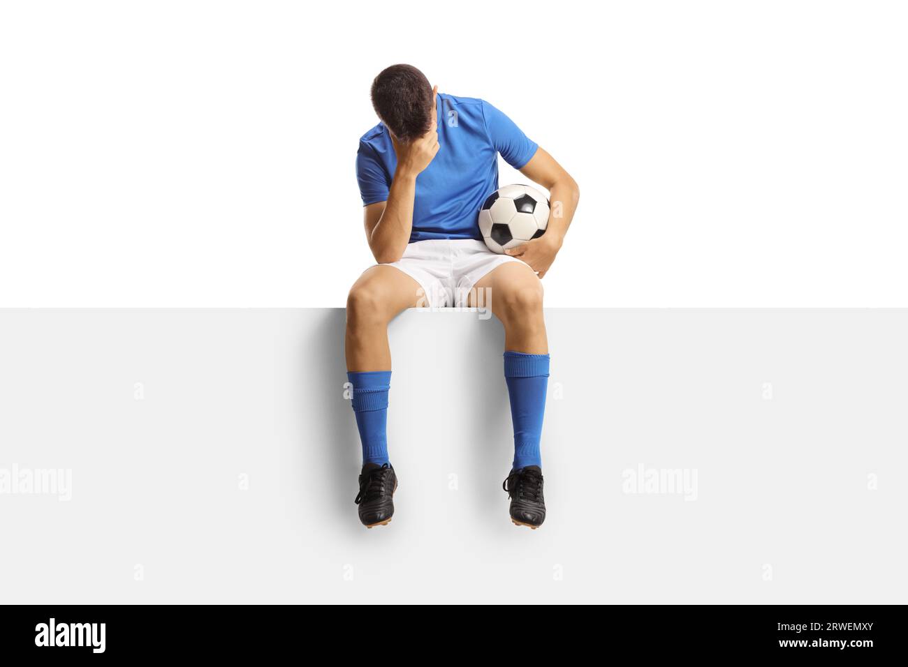 Sad football player sitting on a blank panel isolated on white ...