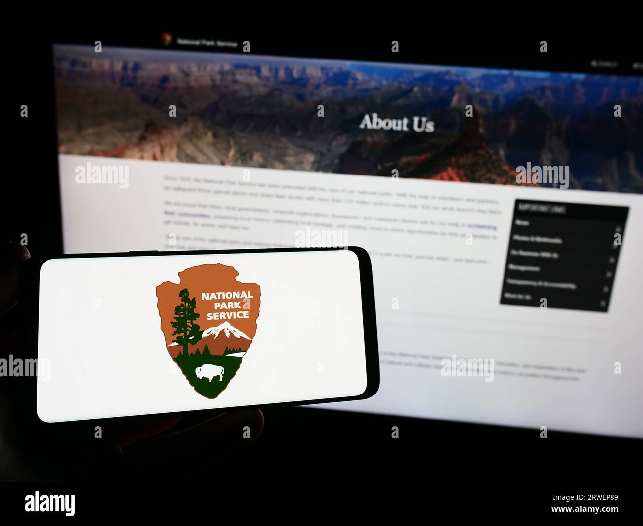 Person holding mobile phone with logo of US agency National Park ...