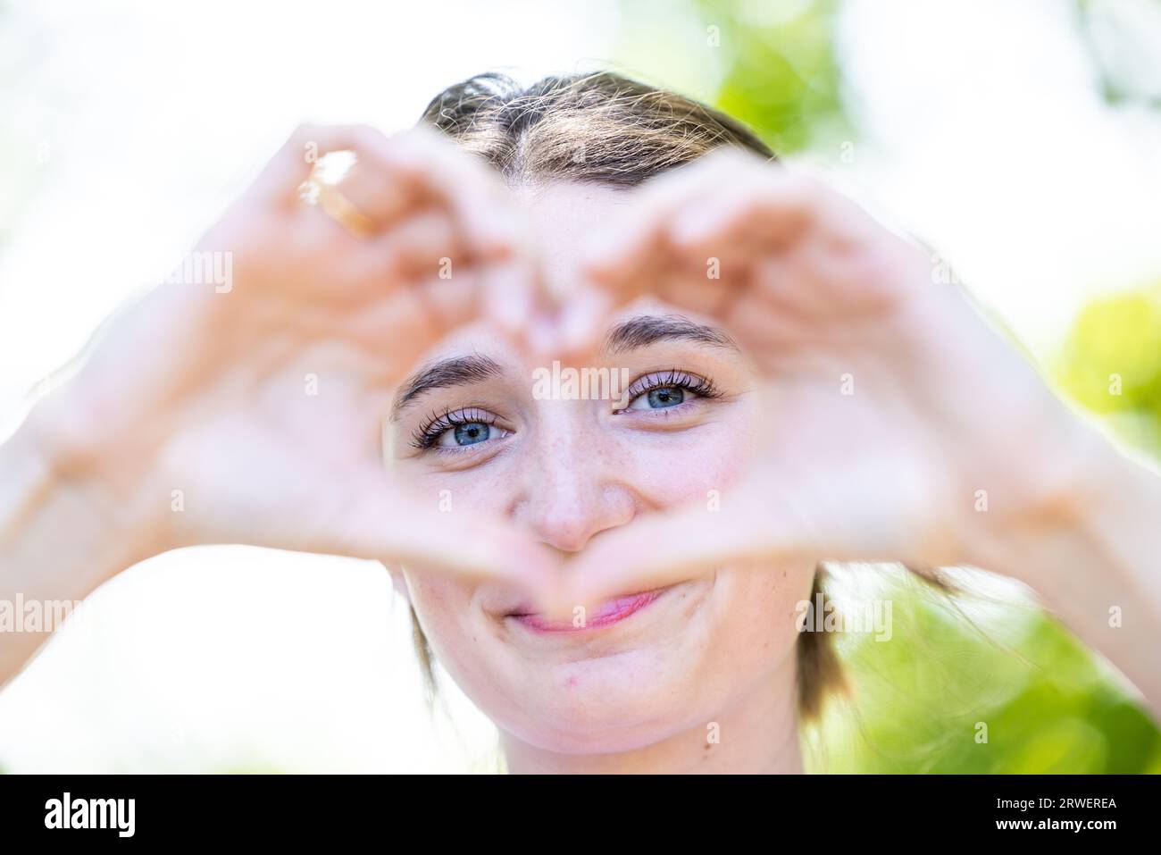 In this captivating close-up, a young woman holds her hands up in a ...