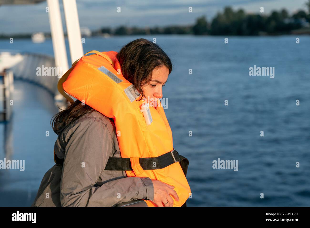 a middle-aged woman wearing an orange life jacket while standing on ...