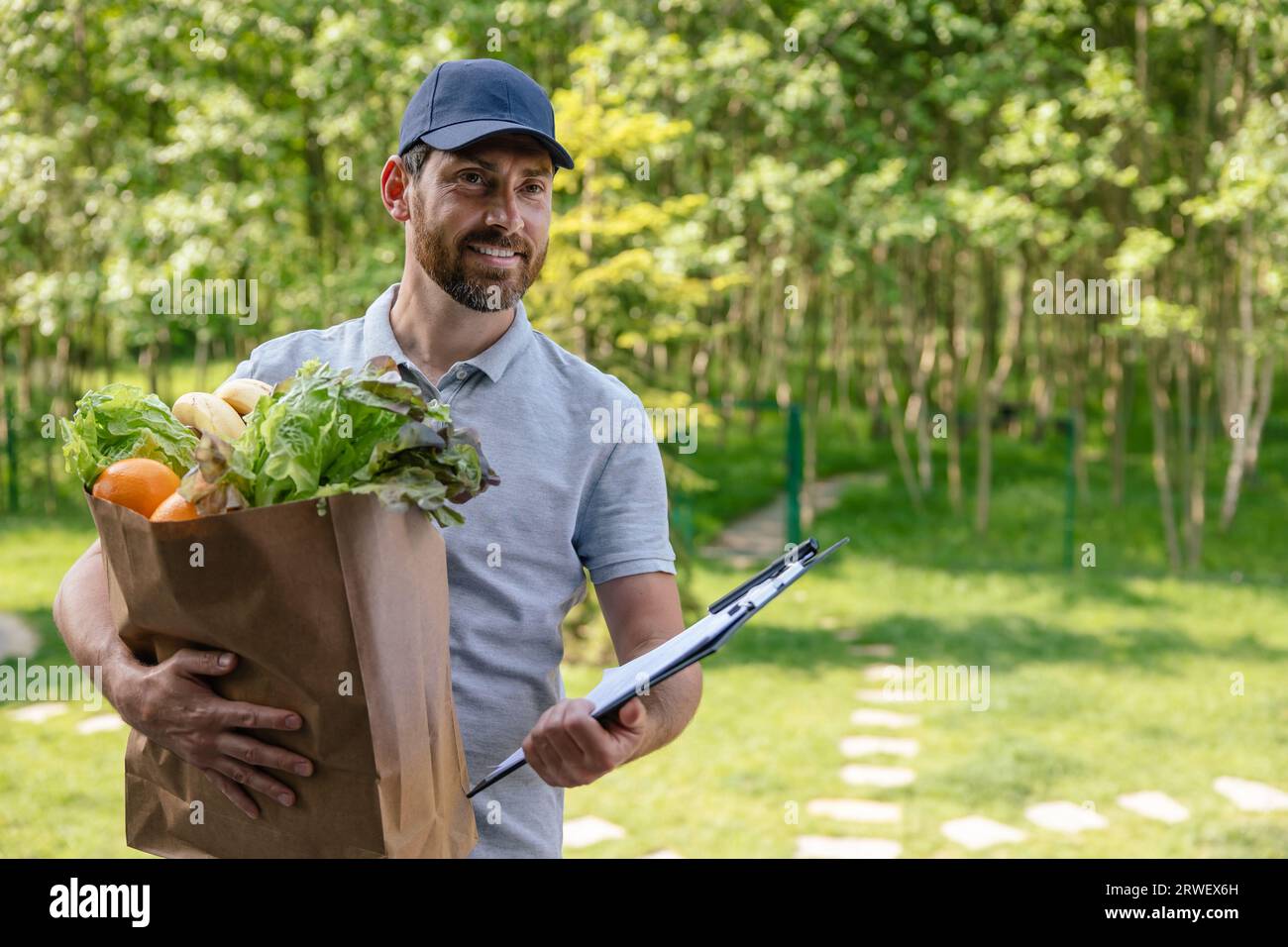 Handsome delivery man carrying package box of grocery food from store ...