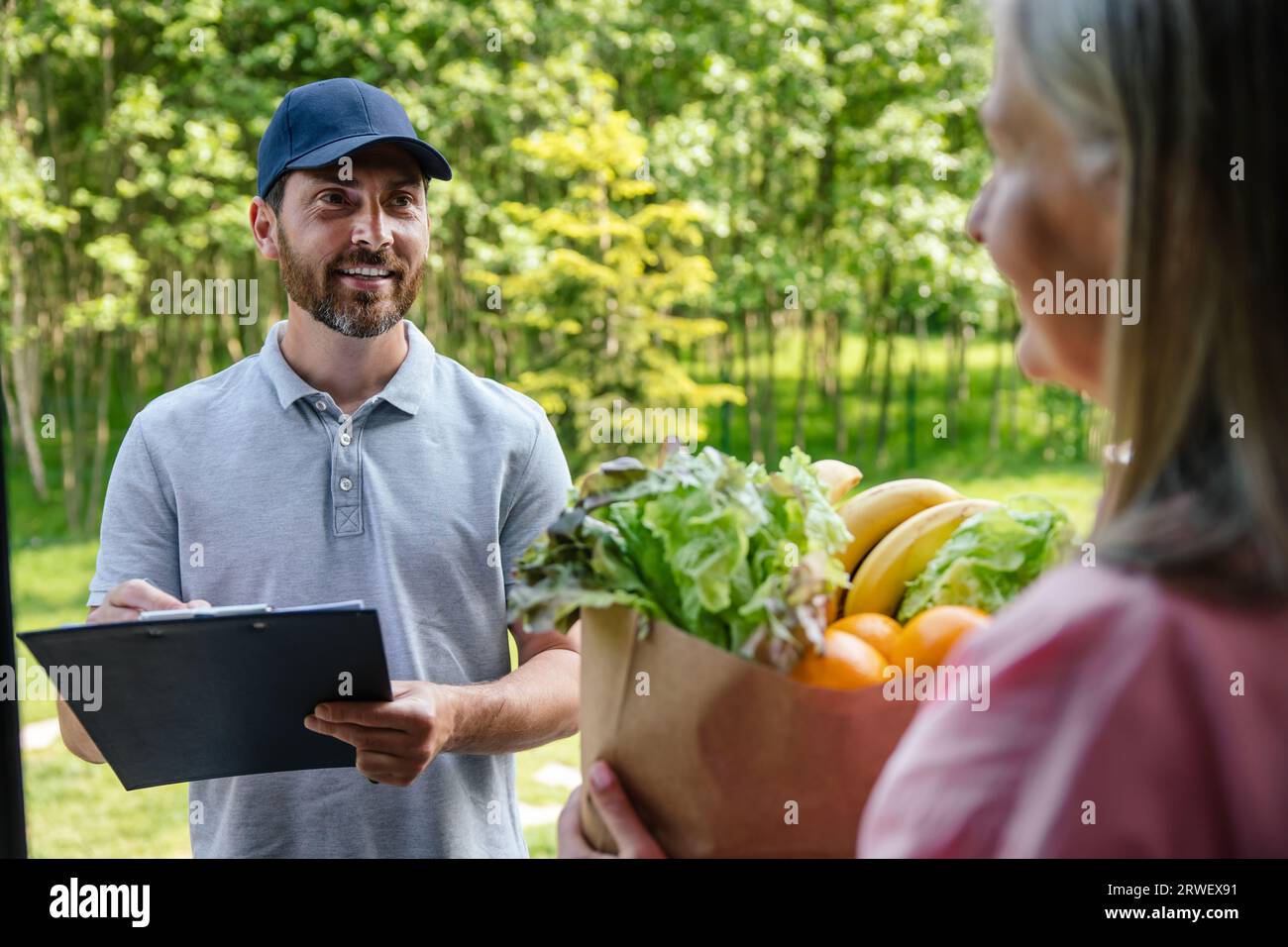 Courier service worker delivering fresh food to woman client signing ...