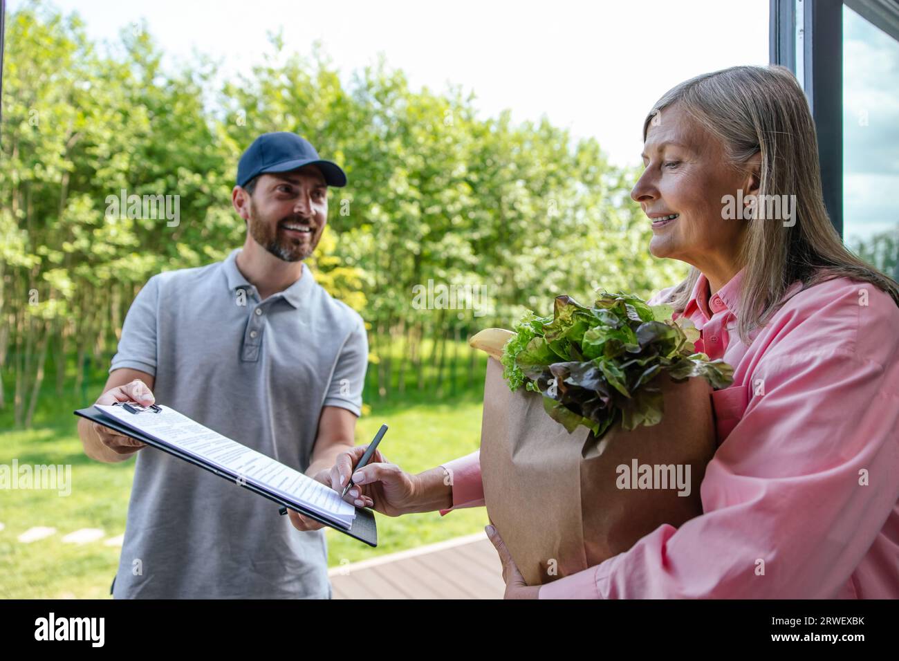 Courier service worker delivering fresh food to woman client signing ...