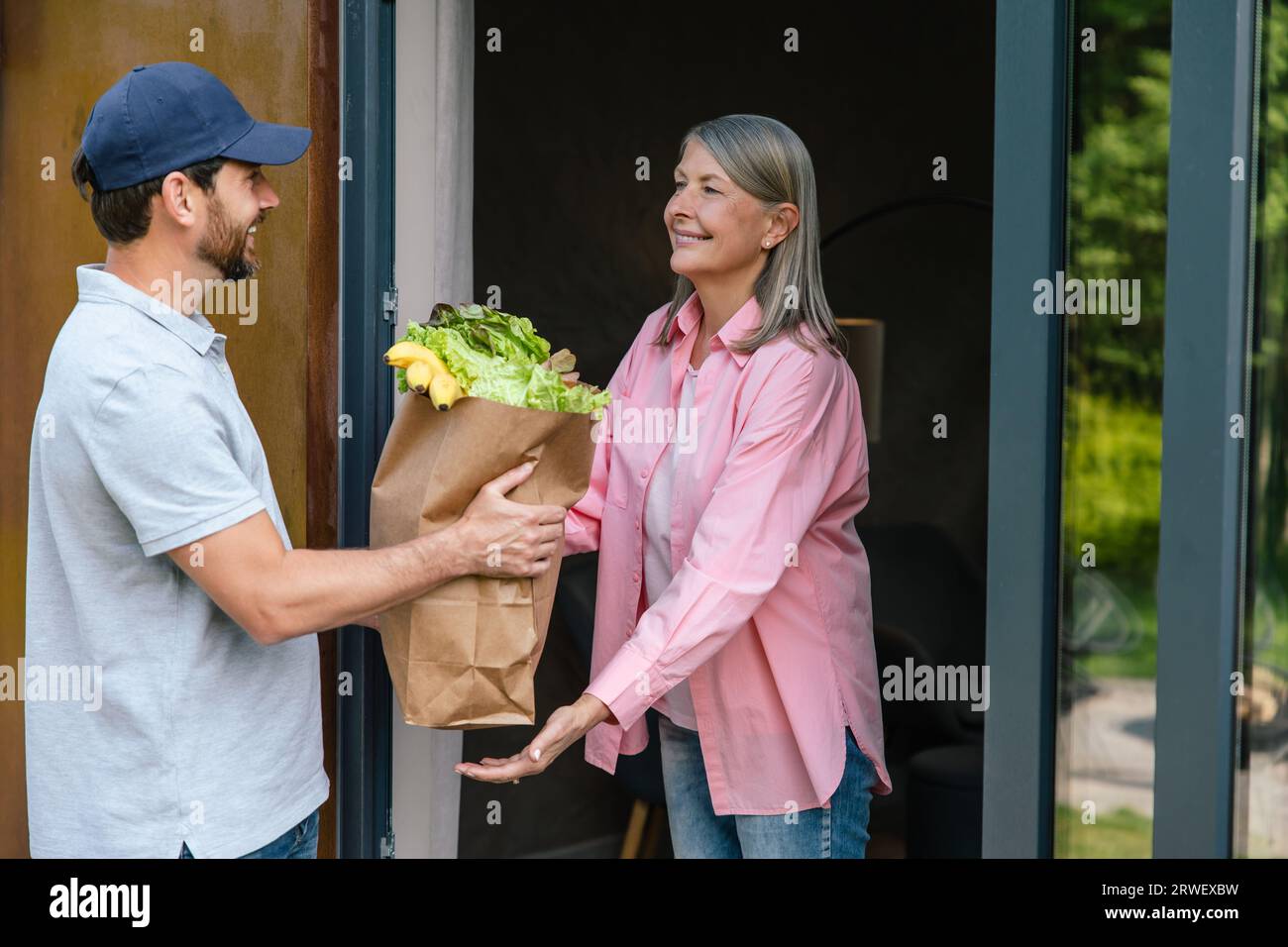 Courier man delivering vegetables to woman at home Stock Photo - Alamy