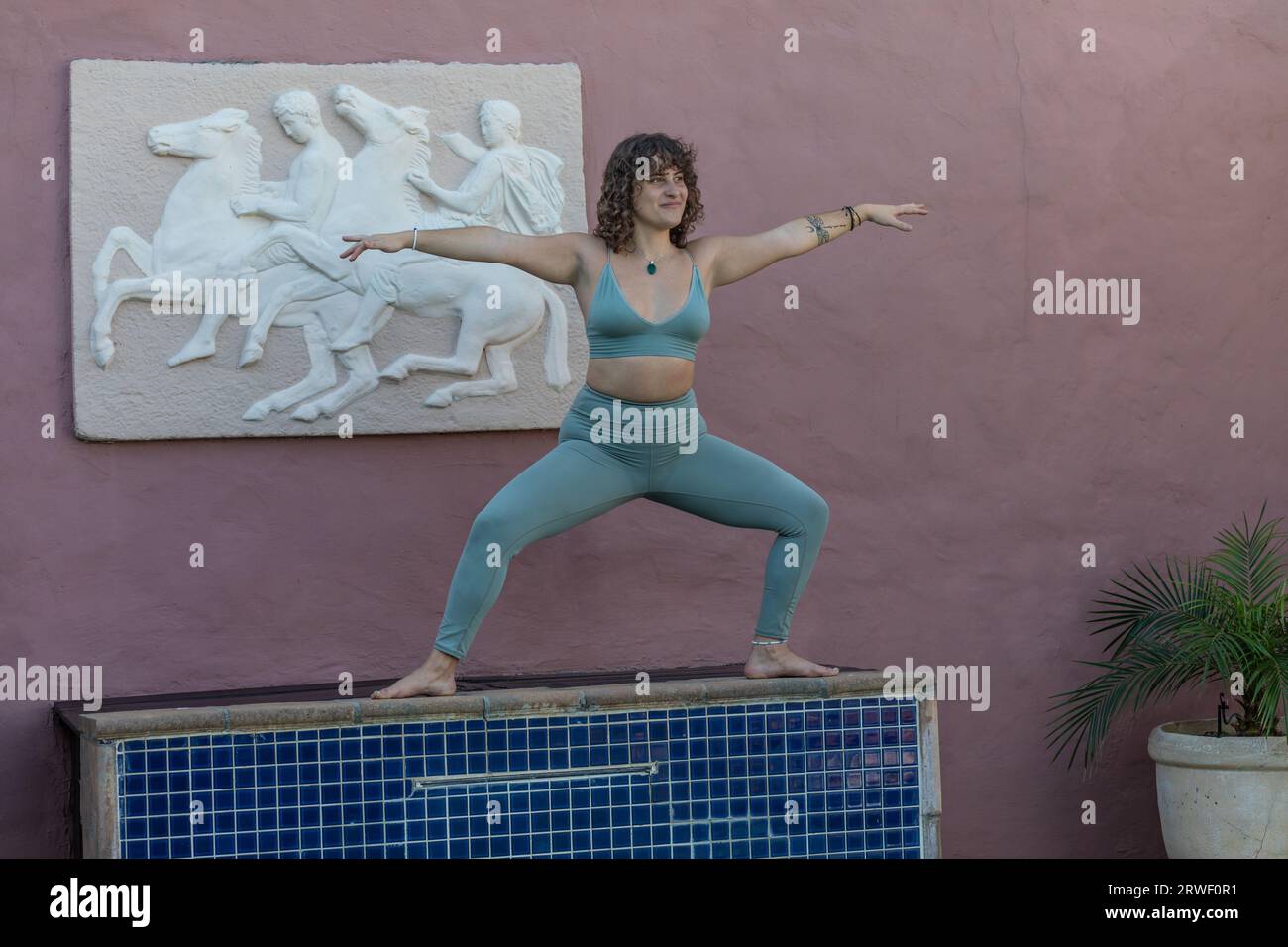 A young woman outdoors gracefully stands in warrior pose with a vibrant ...