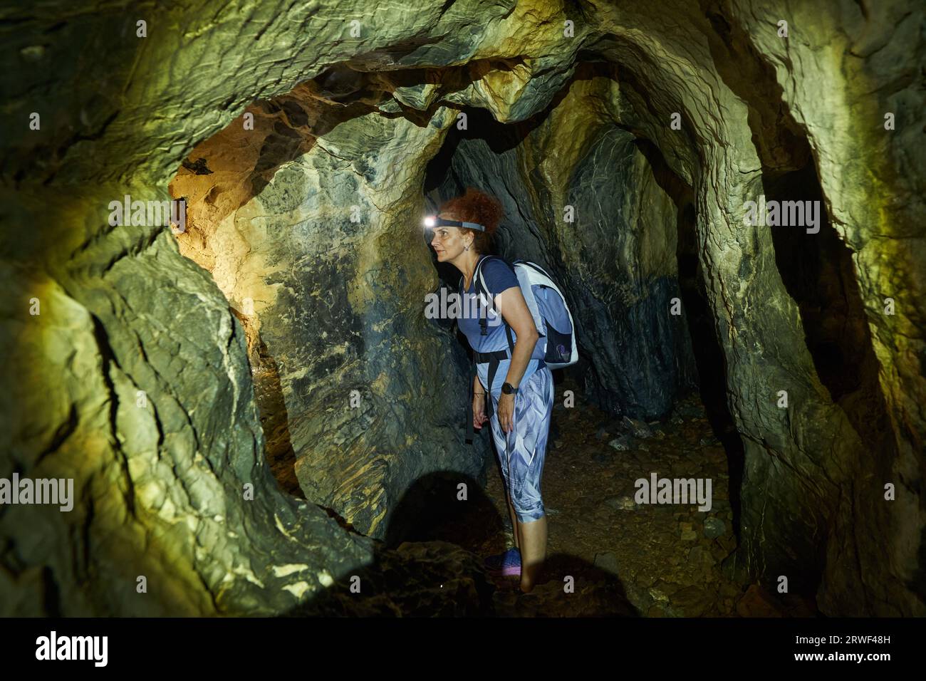 Woman hiker with backpack exploring a cave underground Stock Photo - Alamy