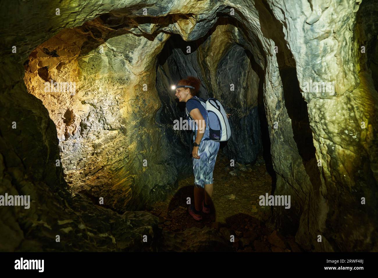 Woman hiker with backpack exploring a cave underground Stock Photo - Alamy